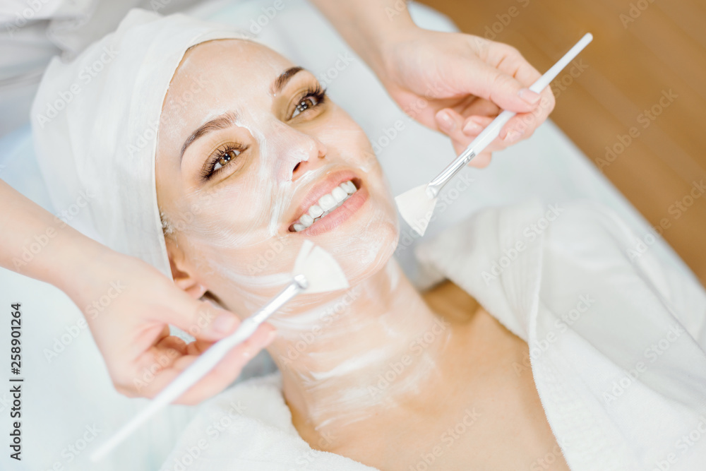 Cosmetology. The cosmetologist applies a cleansing face mask with two ...