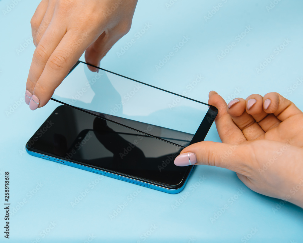 Smartphone with screen protect glass cover in hands. blue background ...