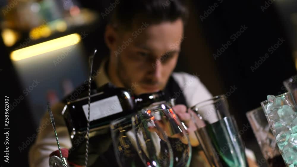 Diagonal view of bar counter with different drink glasses and bartender ...
