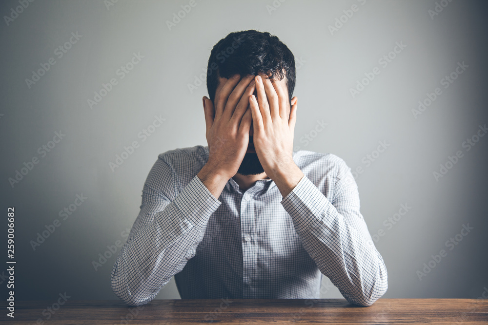 sad man hand in face on desk Stock Photo | Adobe Stock