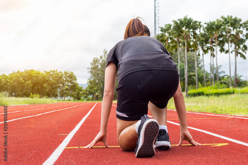 portrait of beautiful young female athlete sitting for ready to running ...