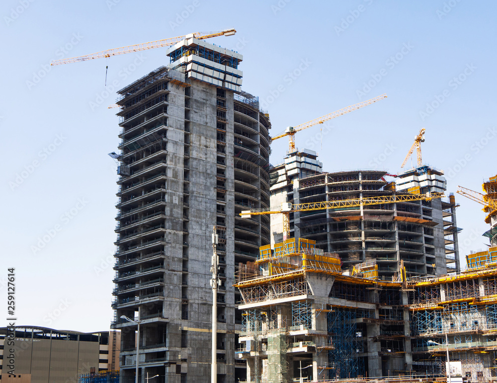 High-rise buildings with yellow cranes and scaffolding at construction ...