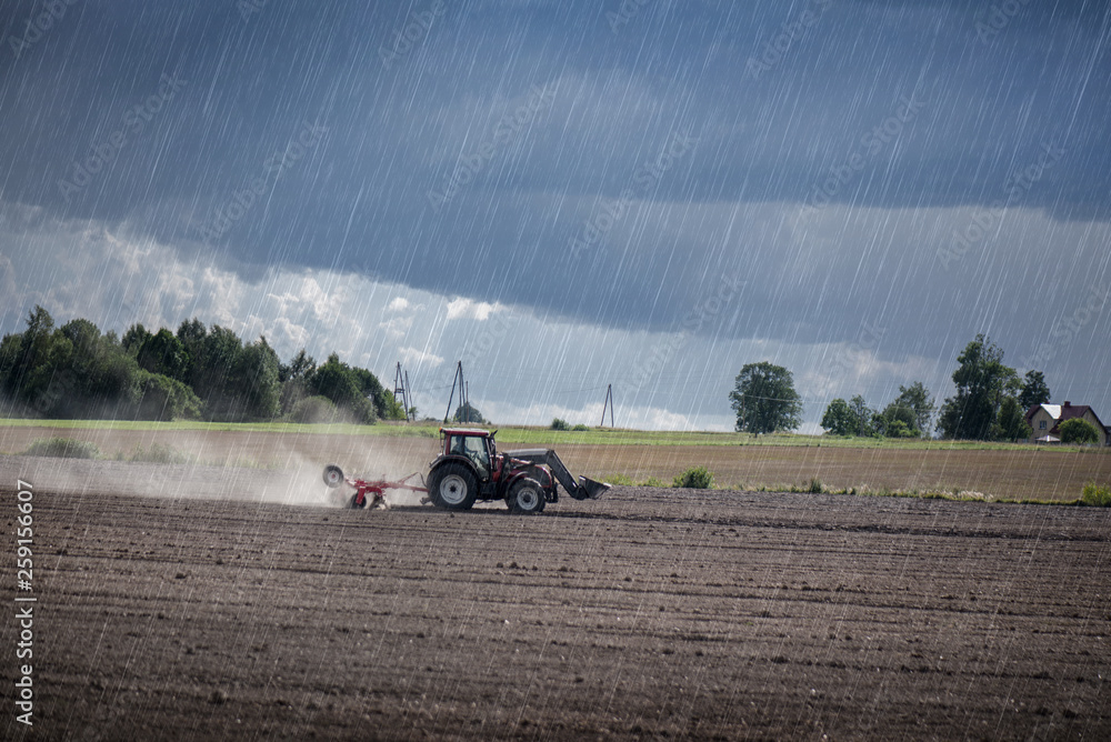 Agricultural background with tractor pulling plow, throwing dust in air ...