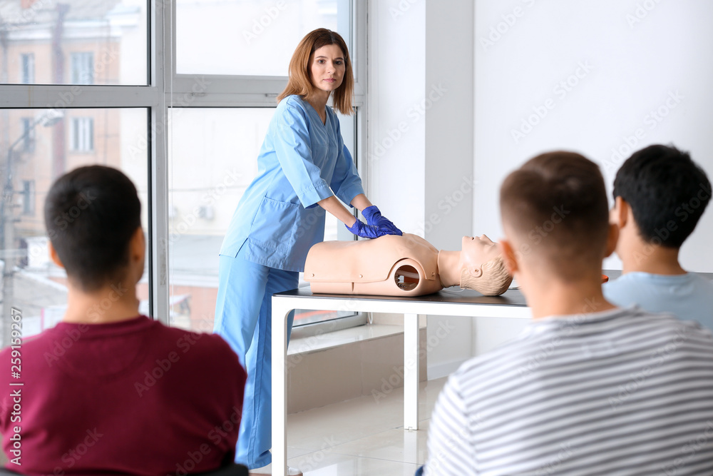 Instructor demonstrating CPR on mannequin at first aid training course ...