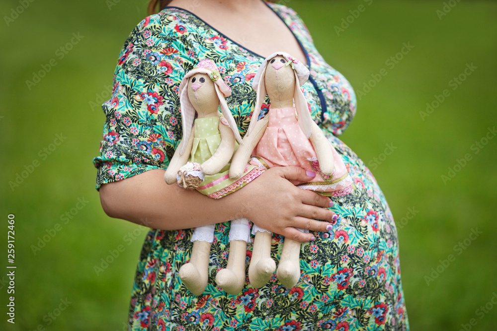 Mom hands holding two rabbits. Pregnant woman's belly. Twins Stock ...