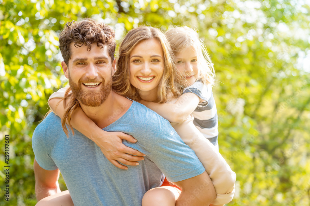 Strong man supporting his family by carrying wife and son piggyback ...