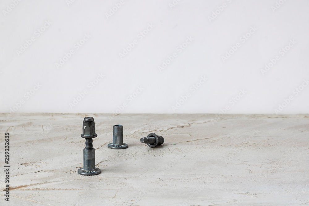 Two metal pop Rivet fasteners, one is joined on grey cement background ...