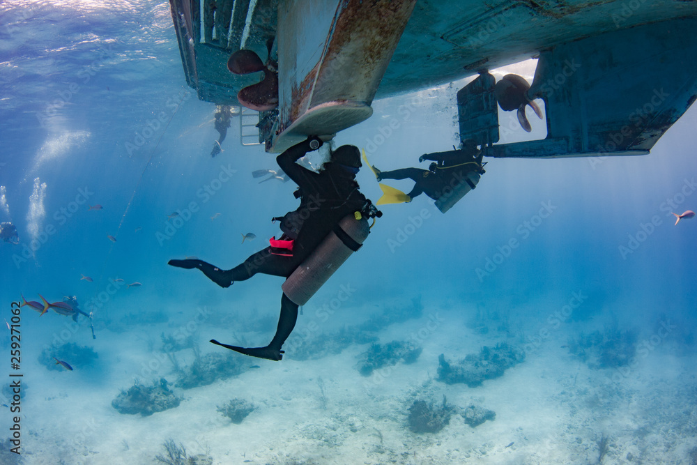 Scuba Divers hold on to ropes and the hull of the boat during their ...