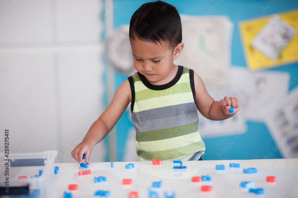 A smart young boy manipulating alphabet letters to form words in ...