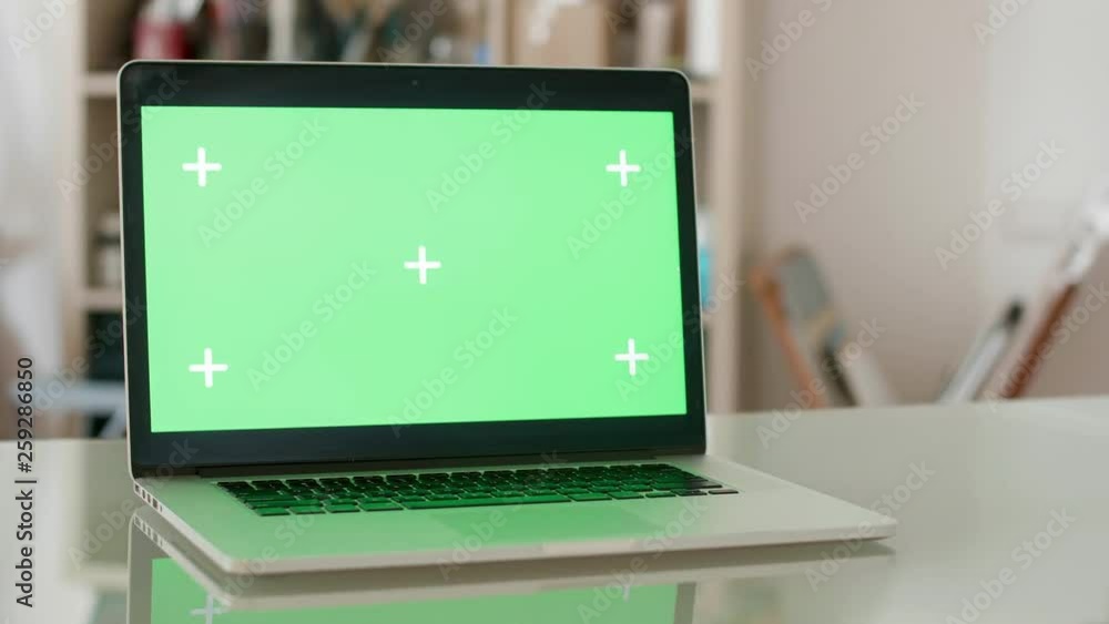 Laptop with green screen on a glass office desk. Designers workshop ...