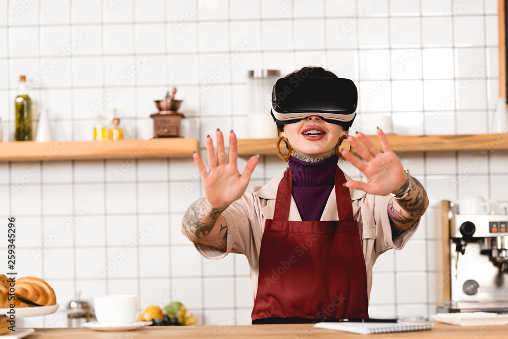 smiling barista in virtual reality headset standing near bar counter in ...