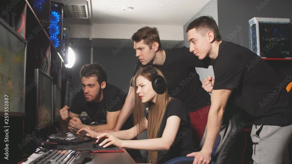 Group of male gamers gather around the female player, thinking hard ...