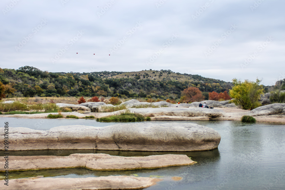Large rocks in the water in the Pedernales River in the autumn in Texas ...