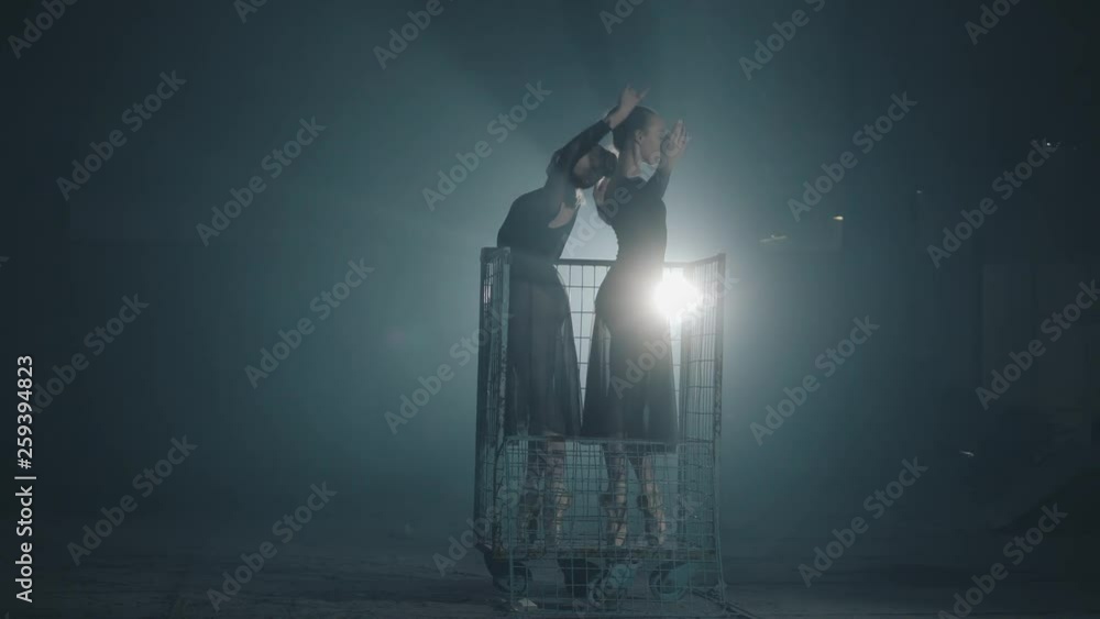 Two slim professional ballerinas dancing in black dress in the studio ...