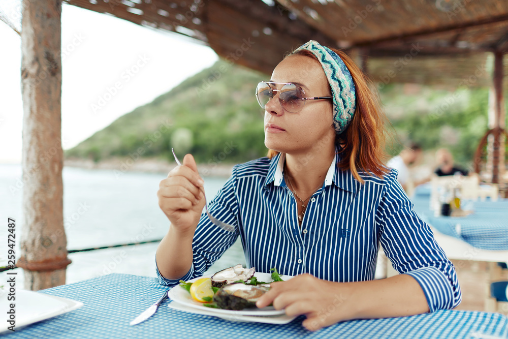 Beautiful young woman eating seafood in a restaurant. Happy young women ...