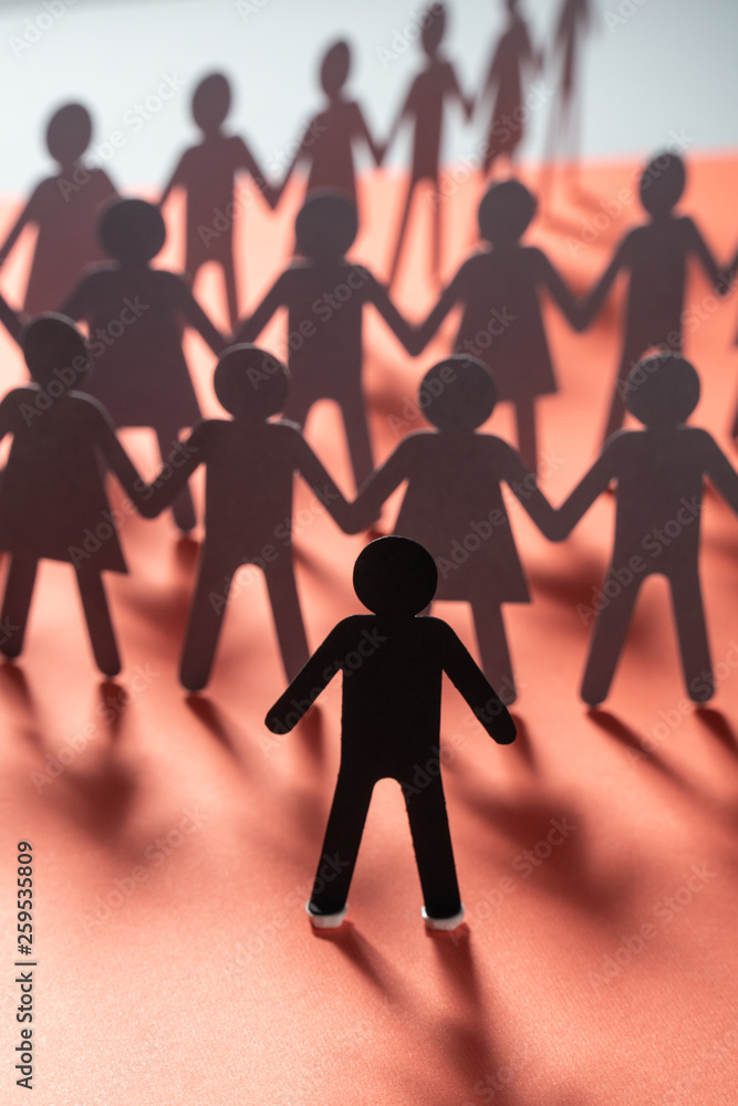 Paper human figure standing in front of paper people holding hands on ...