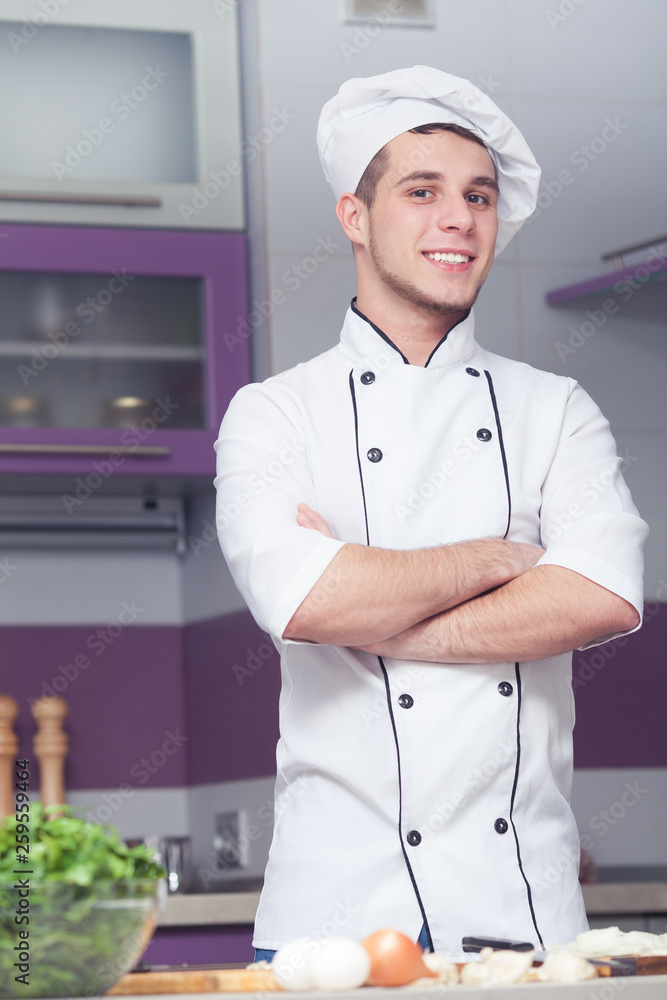 Portrait of funny smiling man in cook uniform with crossed hands posing ...