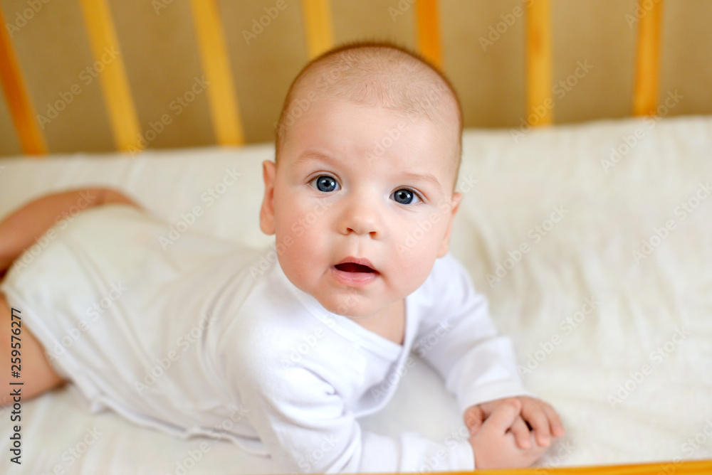 Foto de Cute little baby boy baby 4 months in white clothes lying on ...