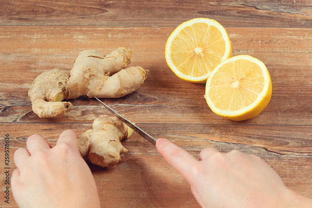 Female hands cut into pieces ginger root for a drink made from fresh ...