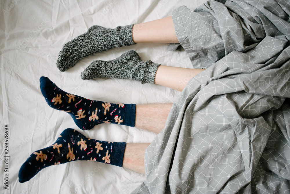 Feet in socks under a blanket in bed Stock Photo | Adobe Stock