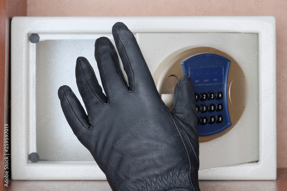 Theft of valuables and money. A black-gloved thief opens the safe door ...