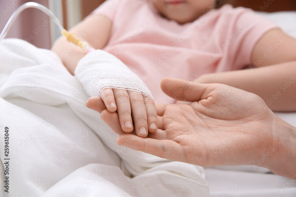 Doctor holding little child's hand with intravenous drip in hospital ...