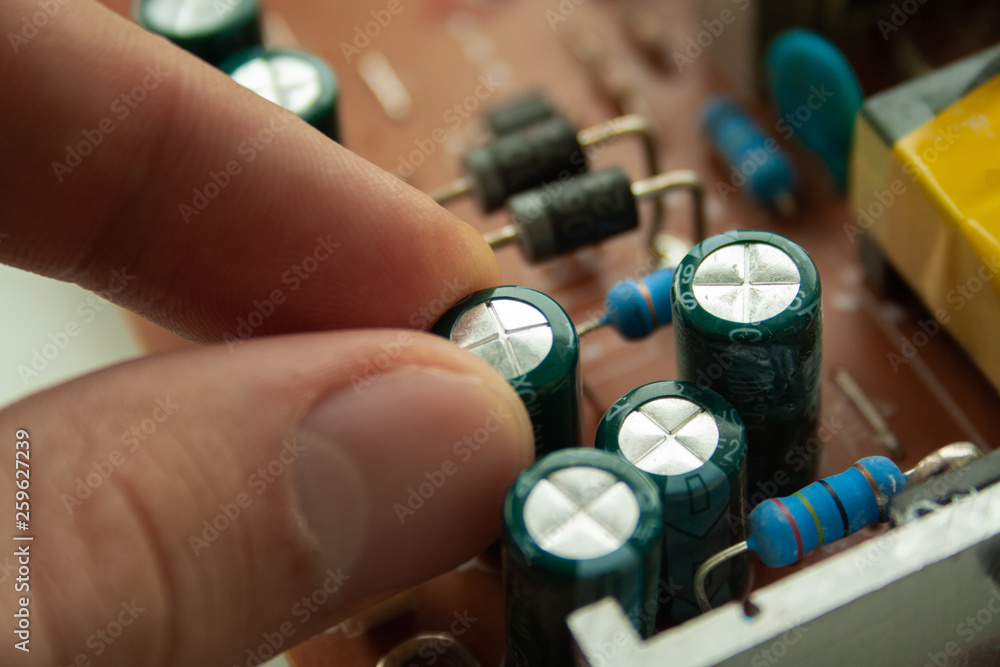 Broken bad old capacitor of computer screen with man's fingers ...