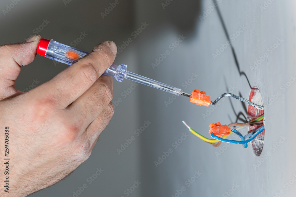 Hands with electrical tester checking the voltage of electrical cables ...
