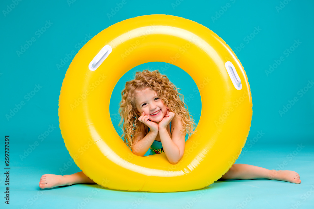 Cute girl in swimsuit holding swimming circle. Isolated on blue ...