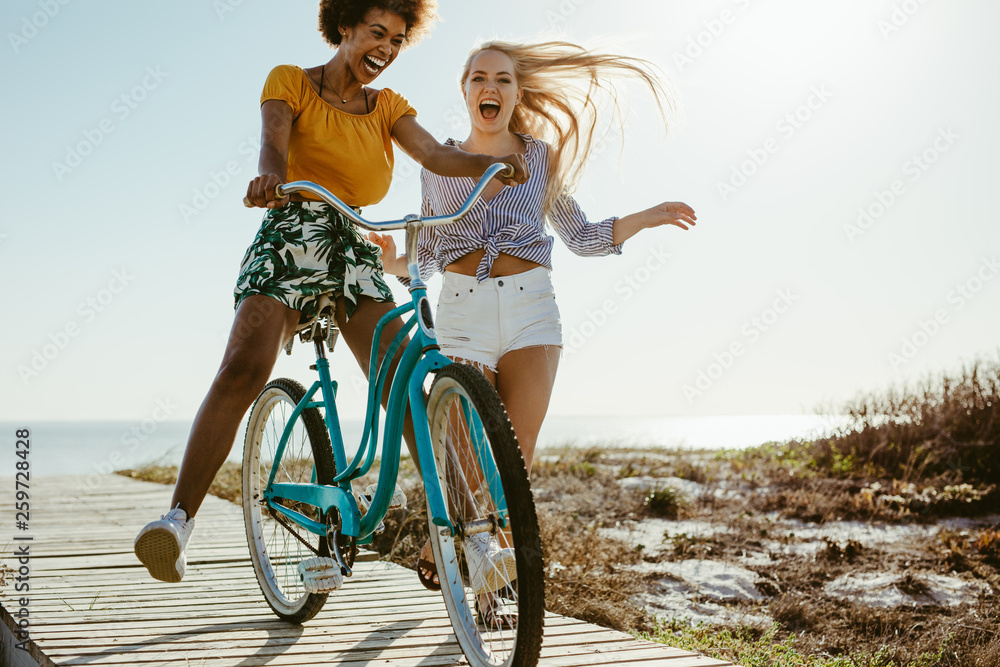 Cheerful girls having fun with a cycle Stock Photo | Adobe Stock