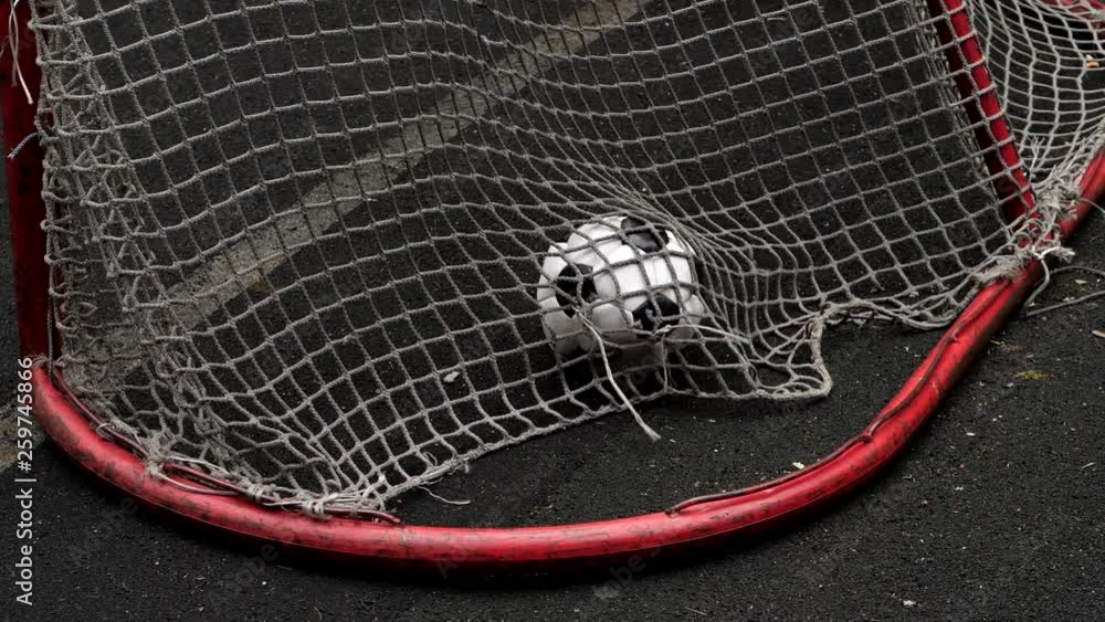 Worn-out and partial deflated soccer ball hit mesh and fall inside ...