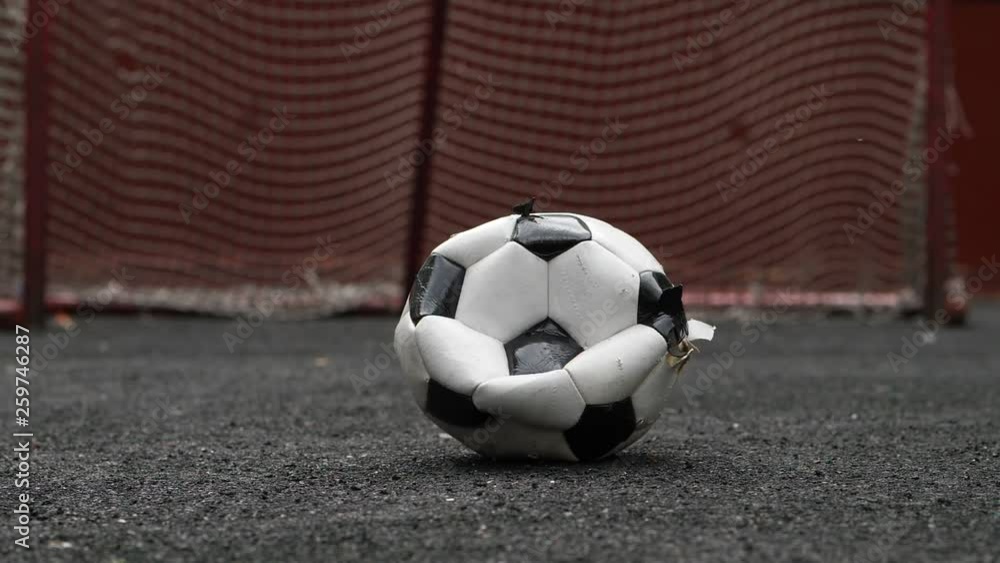 Broken half deflated soccer ball lie on black rubber field against ...