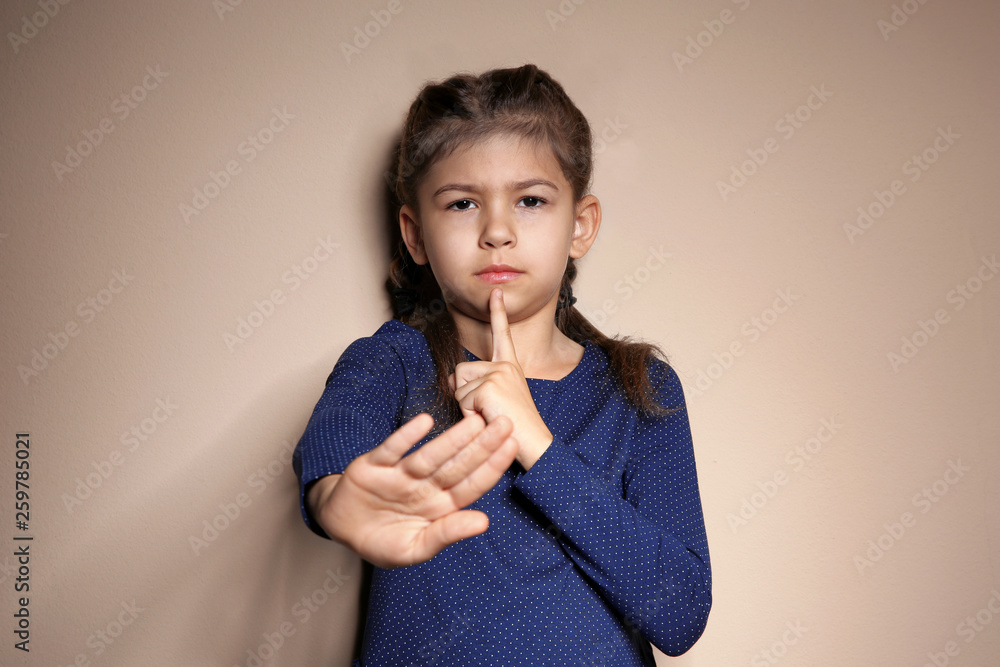 Little girl showing HUSH gesture in sign language on color background ...