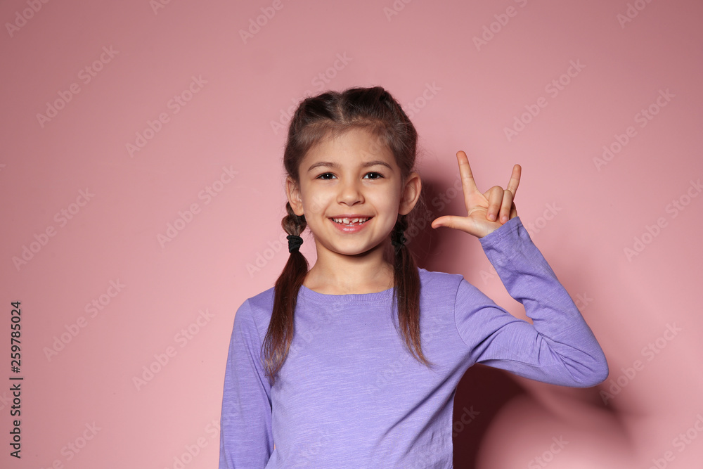Little girl showing I LOVE YOU gesture in sign language on color ...