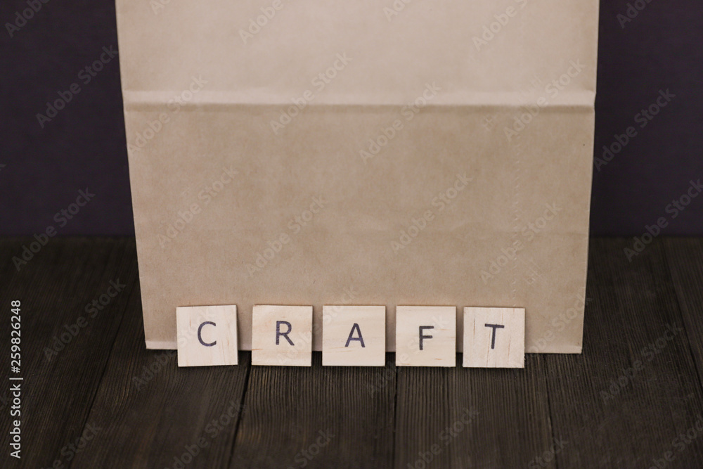 On the tabletop of dark wood is a paper bag of craft paper and the ...