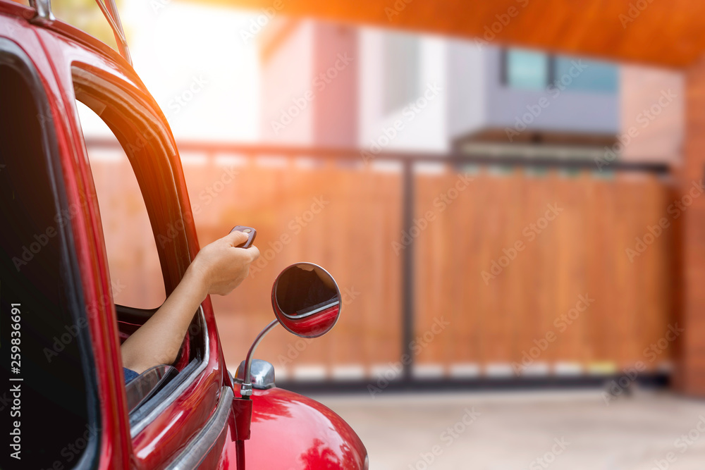 Woman in car, hand using remote control to open auto wooden door with ...