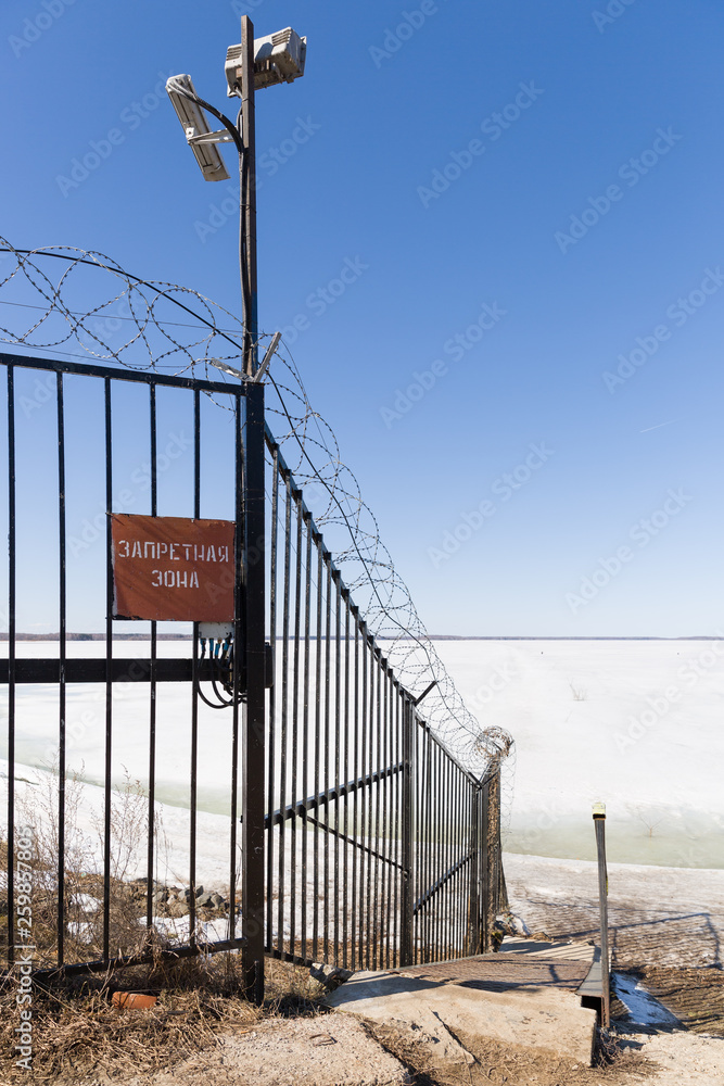 Metal fence with barbed wire and sign in Russian - Forbidden Zone ...