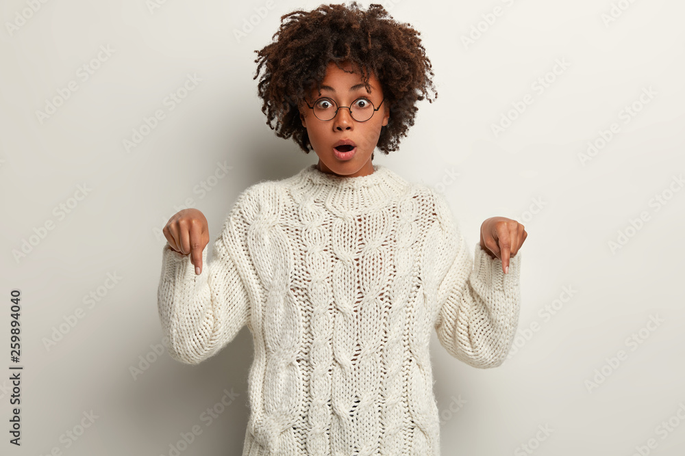 Emotional attractive Afro American woman points down with impressed ...