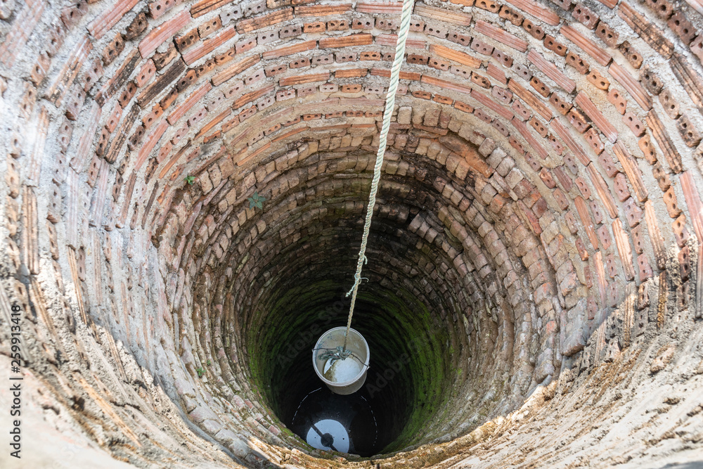 Plastic bucket in old ancient groundwater well. Stock Photo | Adobe Stock