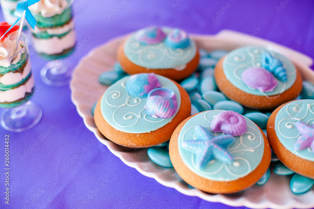 White shell plate full of chocolate candies with blue icing, cookies ...