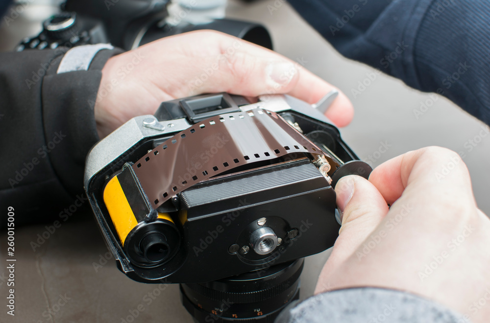 Photographers are putting a roll of film into a retro camera. The ...