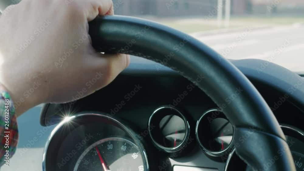Close-up of steering wheel and hand during car driving on street with ...