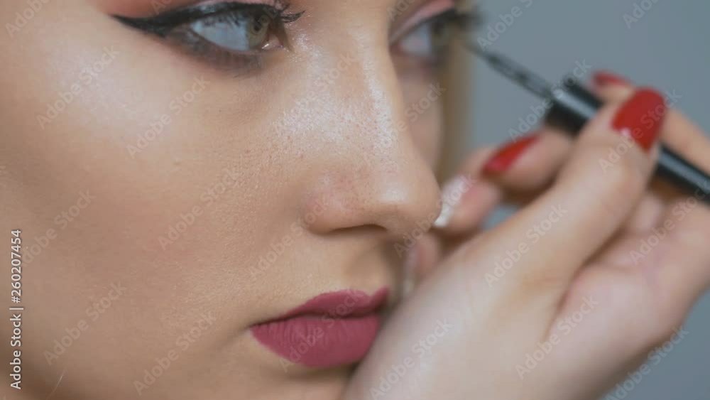 beautiful girl doing makeup in front of the mirror, young woman drawing ...