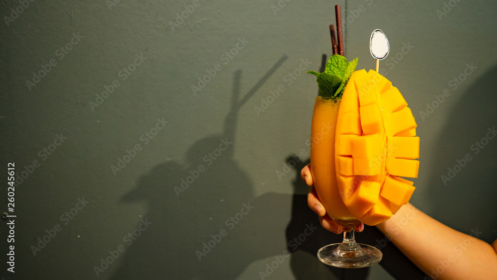 Hand holding A glass with mango juice blended and decorated with ripe ...