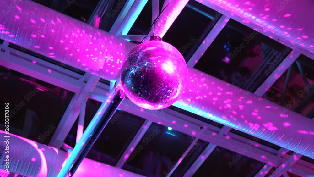 Disco ball rotates under the ceiling in a nightclub, glitters and ...