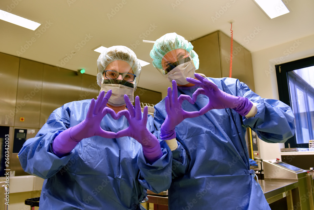 Two women are seen working as medical hygiene technicians. They are ...