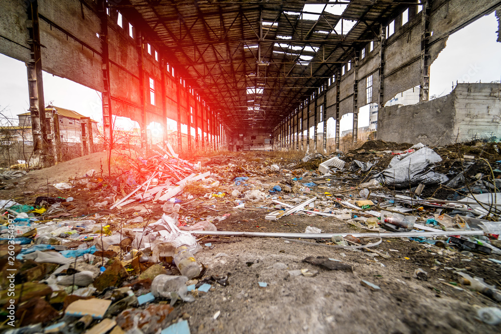Ruined factory or abandoned warehouse hall with a lot of garbage on the ...