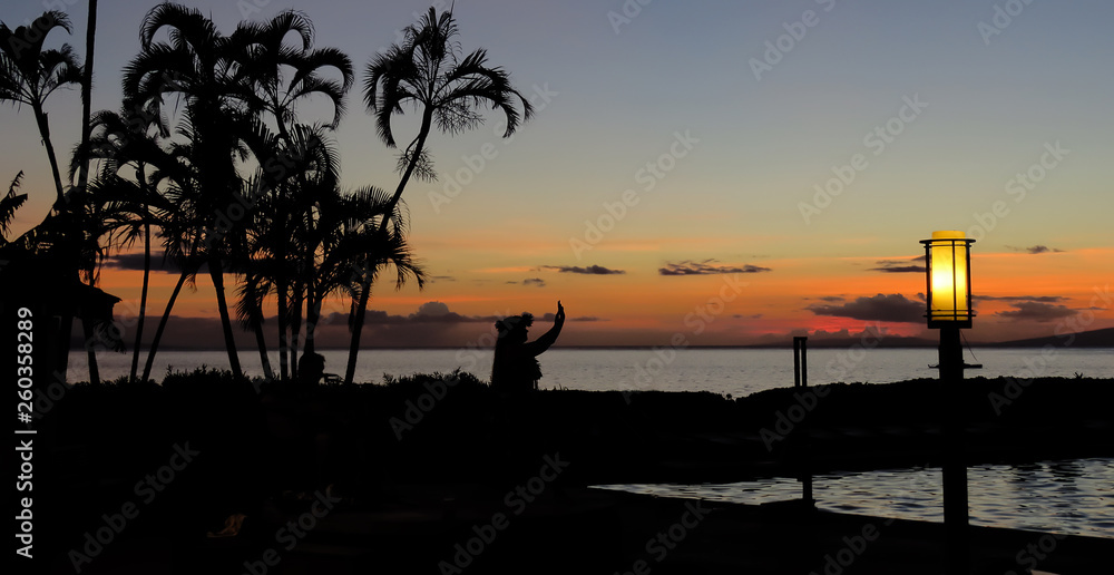 Silhouette of a Hawaiian hula dancer performing near the ocean at ...