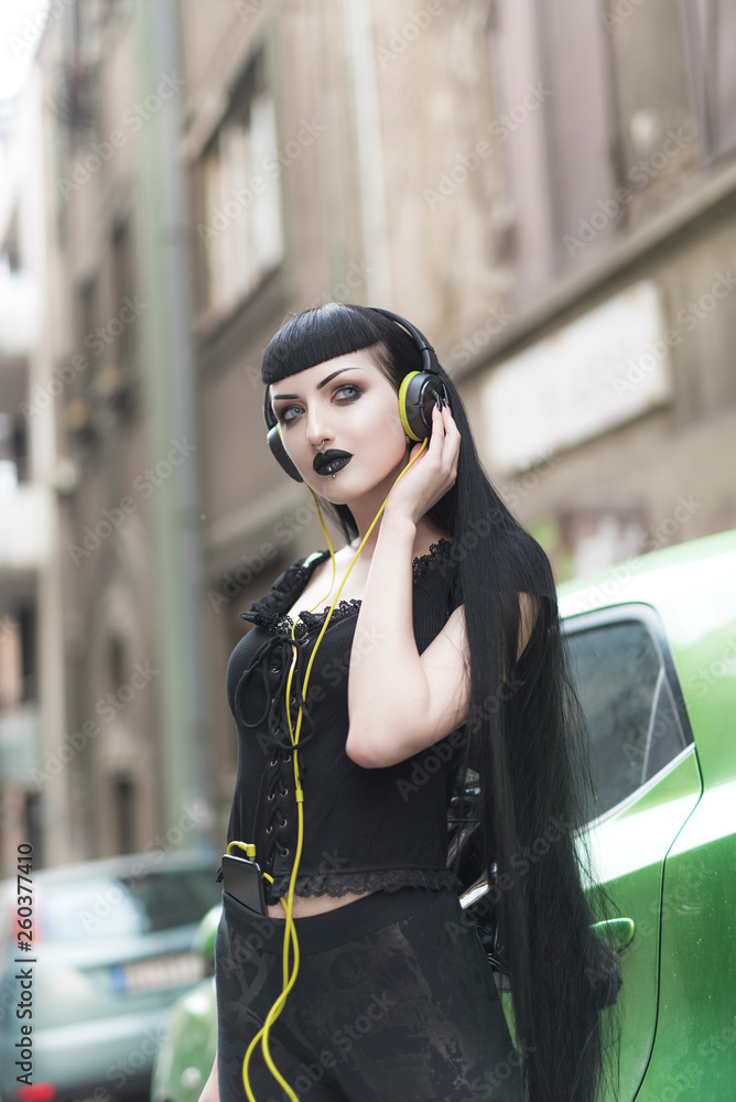 Urban goth girl listening to her favourite music over her big ...