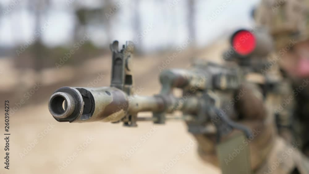Military man is aiming with his assault rifle with a sniper sight in a ...